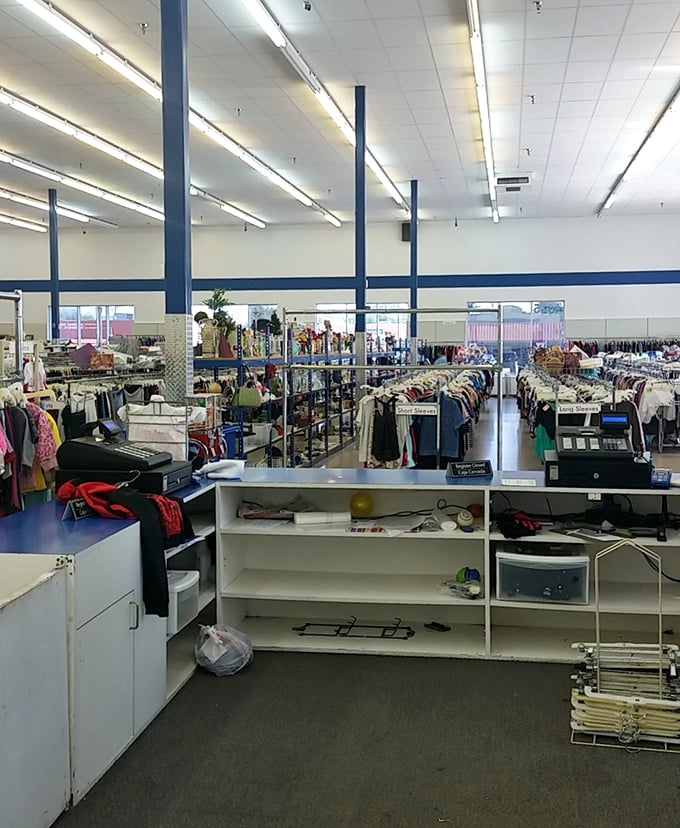 Fluorescent lights illuminate this cathedral of secondhand wonders, where clothing racks stretch toward a horizon of endless possibilities.
