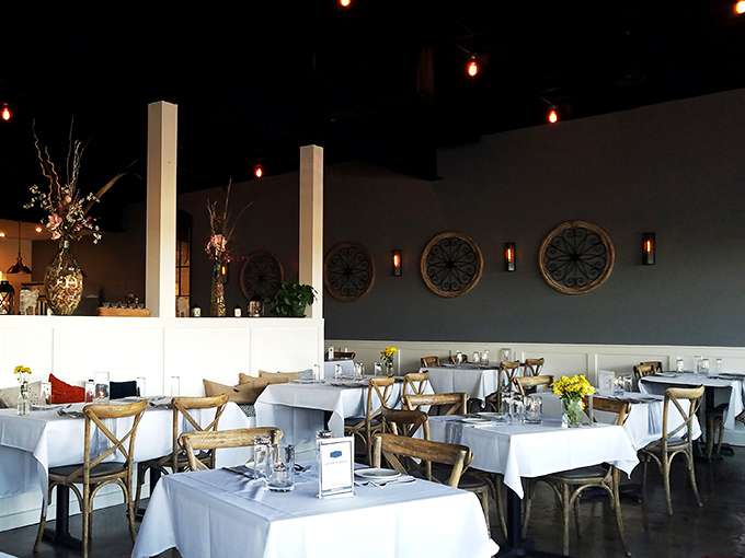 White tablecloths meet rustic wooden chairs in a dining room where elegant meets comfortable. The circular wall accents add just the right touch of coastal sophistication.