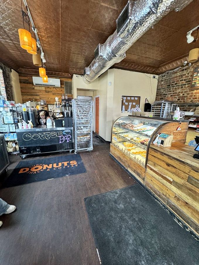 Rustic charm meets sweet indulgence where exposed brick, wooden counters, and that curved display case create the perfect donut sanctuary.