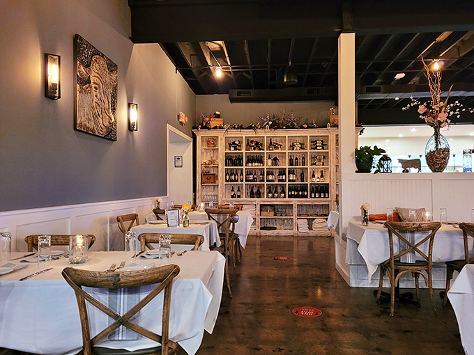 Elegant simplicity defines the dining room, where white tablecloths meet rustic wooden chairs. The impressive wine display isn't just decoration&mdash;it's foreshadowing for the perfect pairing adventure ahead.