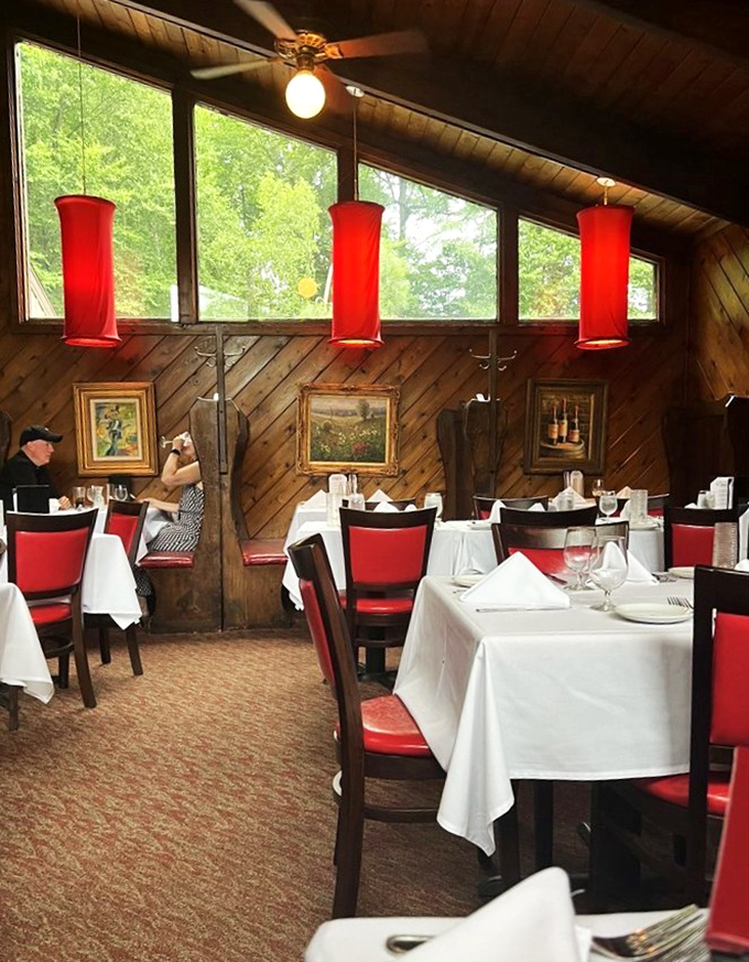 Diagonal wood paneling, crimson chairs, and forest views create the perfect rustic-meets-refined atmosphere where memorable meals unfold.