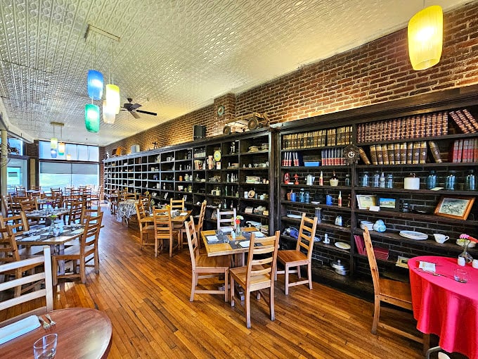Bookshelves line the walls like culinary encyclopedias while the pressed tin ceiling reflects both light and history. This dining room feels like the library Beauty's Beast would build if he were a foodie.