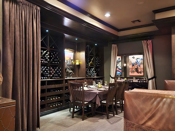 Wine bottles stand at attention like patient soldiers, guarding this intimate private dining space where memorable meals and conversations unfold beneath western-inspired artwork.