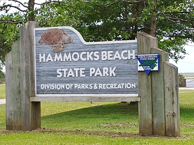 The weathered wooden welcome sign stands as both invitation and promise &ndash; adventure awaits beyond this humble marker.