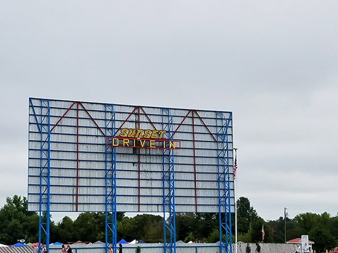 The iconic blue steel framework and illuminated "Sunset Drive-In" sign stands as a beacon of nostalgia against the Missouri sky.