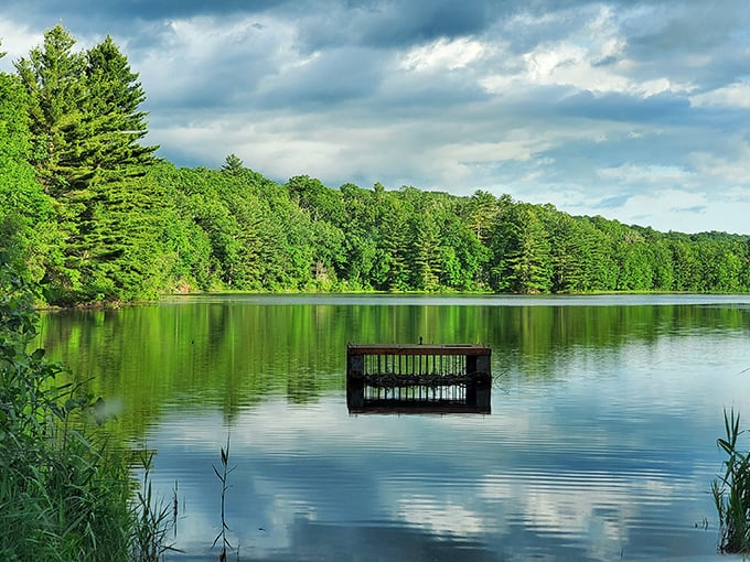 Breakneck Pond glistens like a mirror, reflecting the surrounding pines in a moment of perfect tranquility.