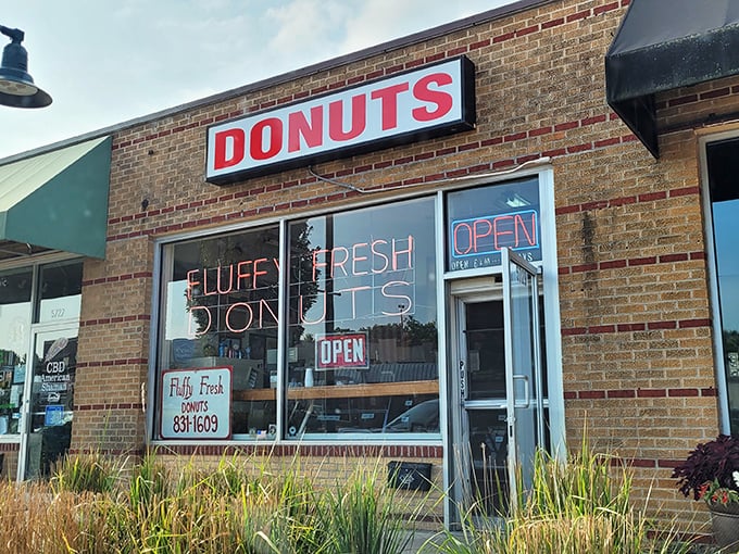 The red DONUTS sign at Fluffy Fresh calls to sweet-toothed travelers like a sugary lighthouse in a sea of chain restaurants.