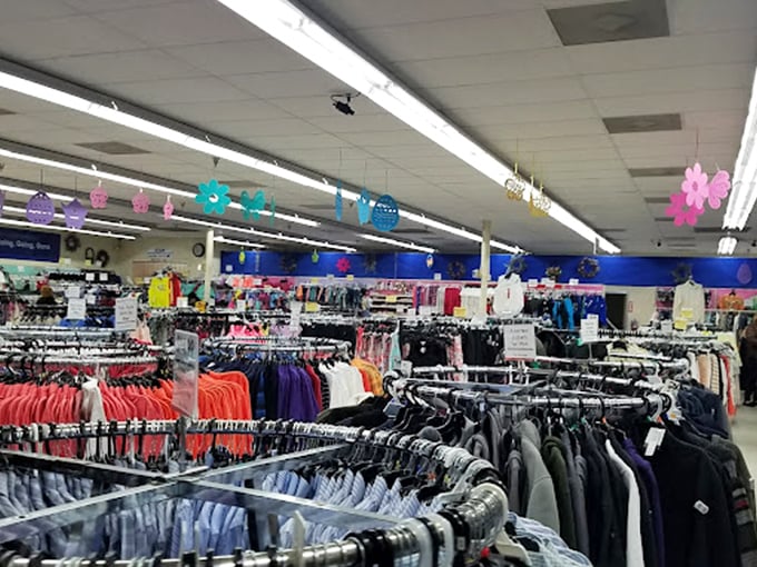 Clothing racks stretch like a rainbow of possibilities, each aisle a new adventure in affordable fashion. The paper flowers overhead add a touch of whimsy.