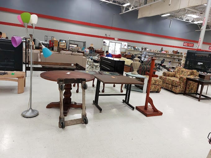 That colorful floor lamp has stories to tell, while those wooden tables patiently wait for their second act in someone's dining room drama.