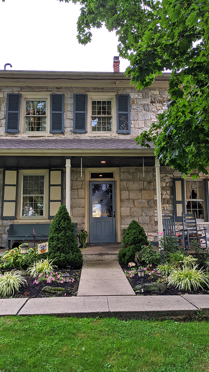 The farmhouse entrance, framed by meticulous landscaping, promises the kind of welcome that Hallmark movies spend millions trying to recreate