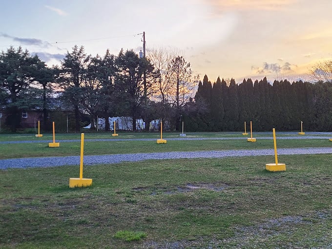 Yellow parking poles stand like sentinels at dusk, patiently waiting for the evening's automotive audience to arrive. 