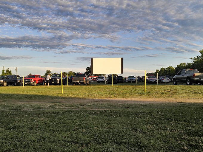 A perfect summer evening unfolds beneath dramatic clouds as moviegoers await showtime on the gently sloped viewing grounds.