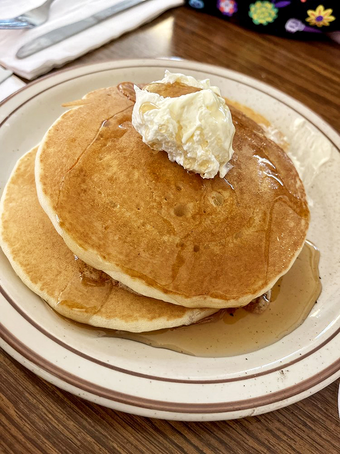 That perfect moment when maple syrup cascades over a golden pancake summit, crowned with a dollop of whipped butter.