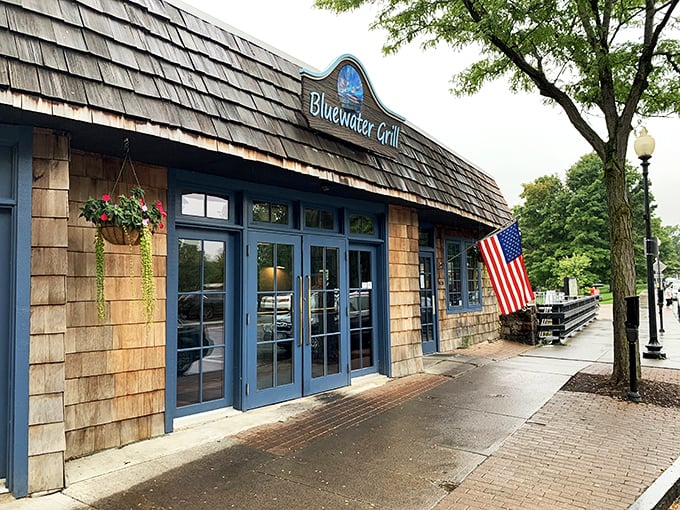 Blue Water Grill welcomes hungry travelers with cedar-shingled warmth, American flag proudly waving&mdash;like a nautical clubhouse where seafood dreams come true.