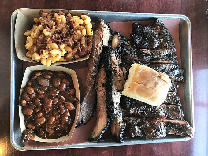 Barbecue nirvana arrives on a metal tray: perfectly barked ribs, tender brisket, and sides that refuse to be overshadowed by their meaty companions.