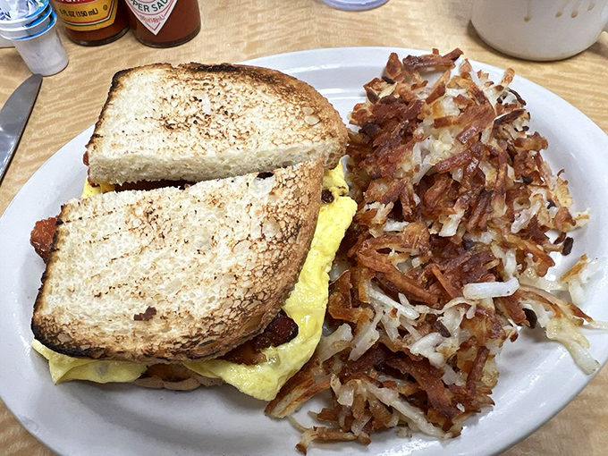 Breakfast sandwich architecture at its finest&mdash;perfectly toasted bread, fluffy eggs, and those hash browns! This isn't just breakfast; it's morning salvation on a plate.