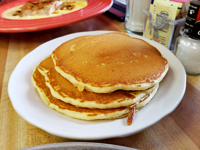 Golden-brown perfection in stack form. These aren't just pancakes; they're edible pillows that transform maple syrup into liquid happiness.