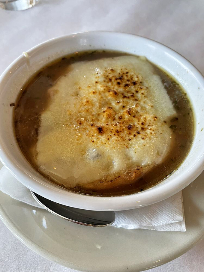 The legendary French onion soup arrives like a warm hug in a bowl &ndash; that melted cheese canopy hiding a treasure of caramelized goodness below.