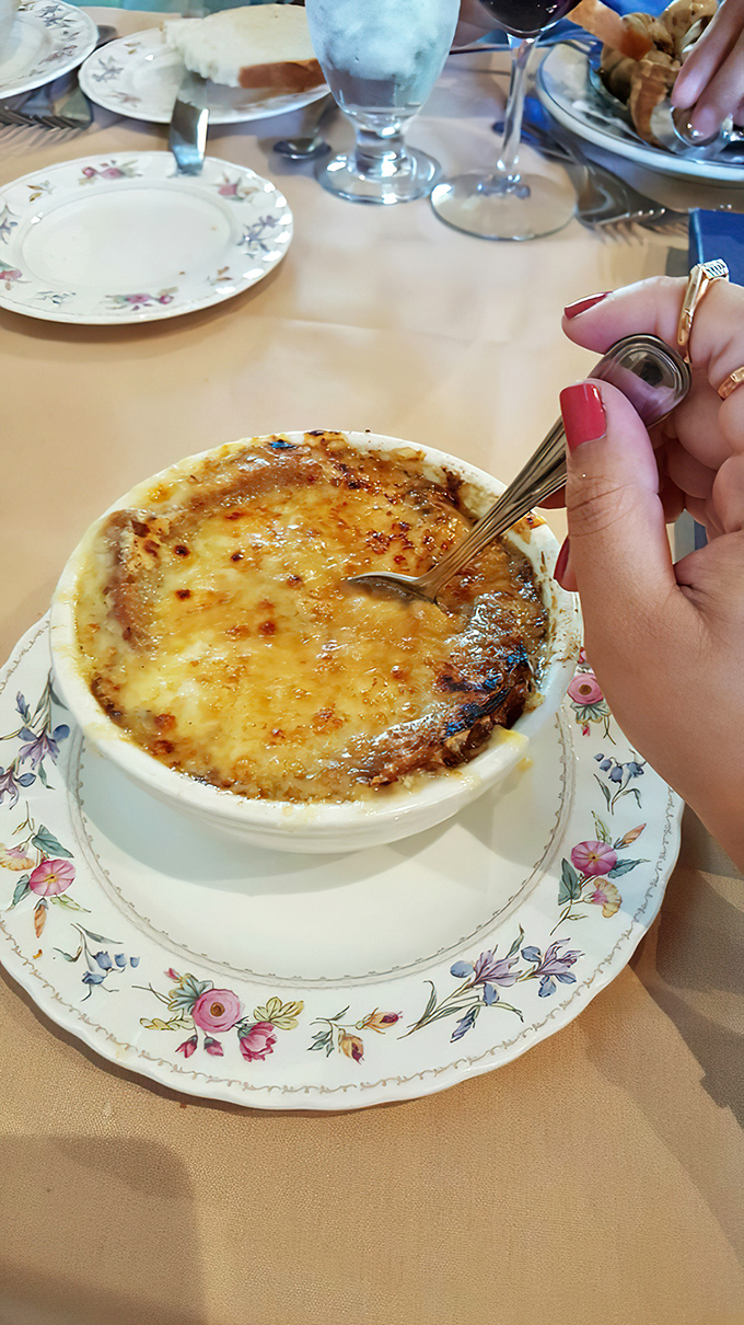 Behold the crown jewel: French onion soup with a cheese canopy so perfect it deserves its own architectural award.