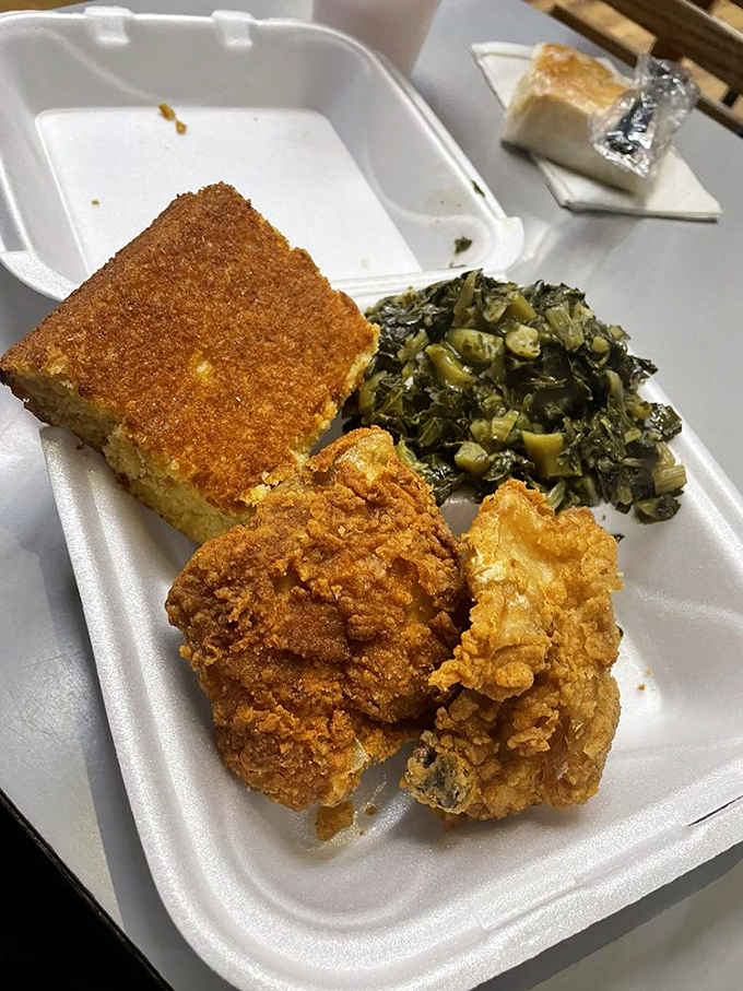 Southern trinity perfection: golden fried chicken, slow-simmered collards, and cornbread that would make your grandmother both jealous and proud.
