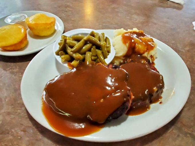 That glossy, mahogany-hued meatloaf practically whispers "resistance is futile" as it lounges in a pool of savory gravy.