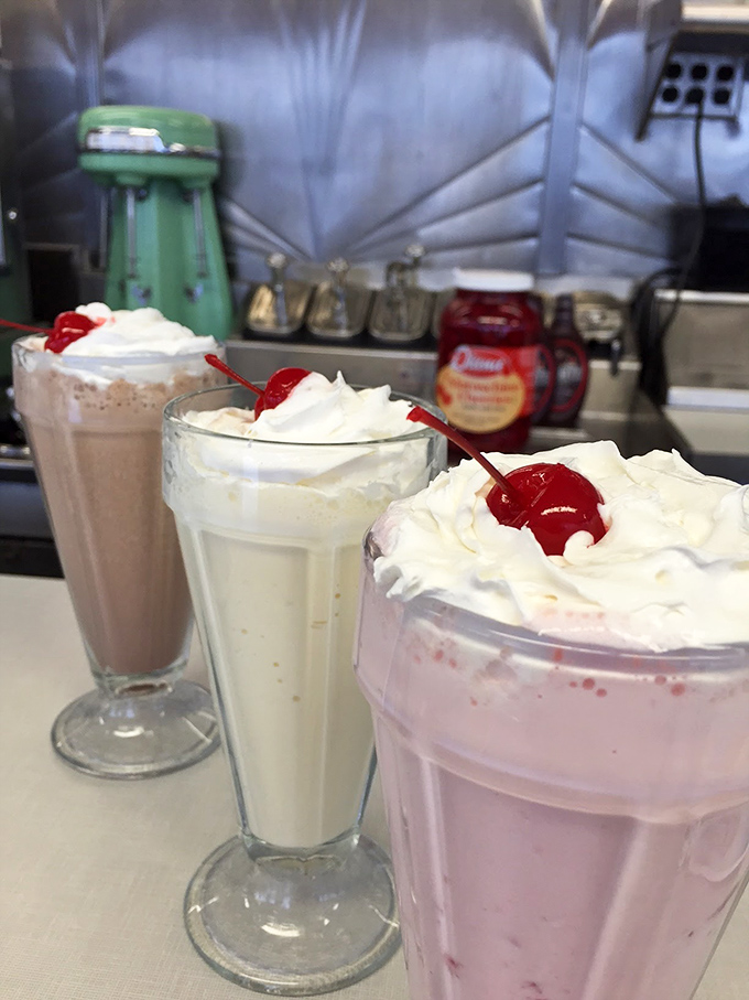 Three generations of milkshake perfection lined up like dairy royalty&mdash;each topped with whipped cream mountains and cherry crowns worthy of their legendary status.