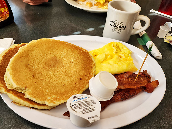 Golden pancakes the size of frisbees share plate space with perfectly scrambled eggs and bacon. The breakfast trinity, executed with diner perfection.