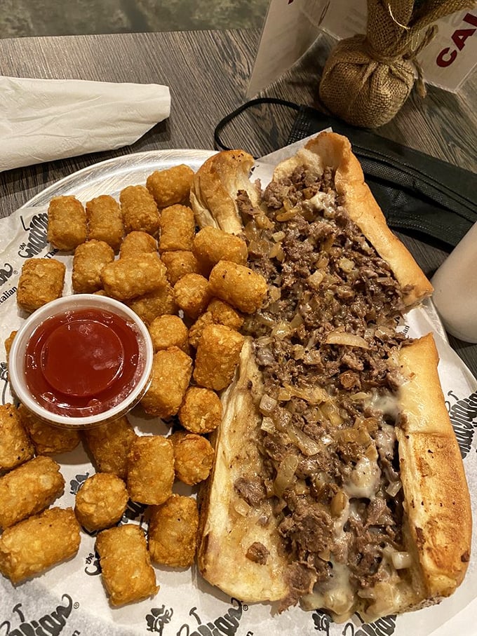 This isn't just a sandwich; it's an architectural masterpiece of thinly sliced beef, melted cheese, and those golden tater tots standing guard.