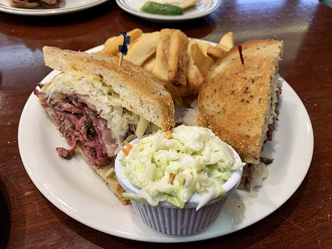 The Reuben arrives like a sandwich celebrity, flanked by crispy fries and coleslaw bodyguards. This is what sandwich dreams are made of.