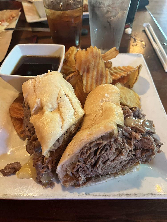 This isn't just a sandwich; it's a masterpiece of slow-roasted beef piled so generously it practically cascades off the bun, with au jus standing by for the perfect dip.