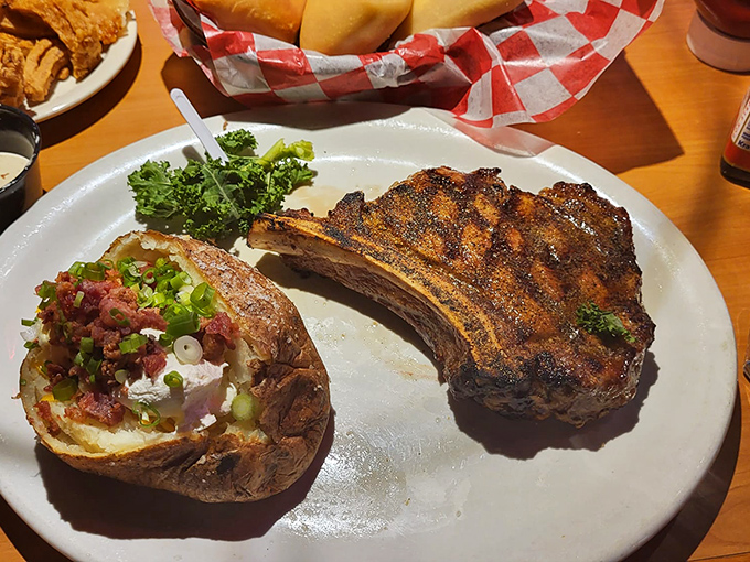 The cowboy's reward after a long day: a perfectly charred bone-in steak alongside a loaded potato wearing its toppings like well-earned medals.