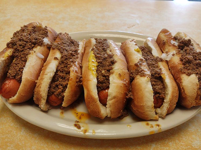 The holy trinity of hot dog heaven: chili, mustard, and onions. Three simple ingredients that create a symphony in a bun. 