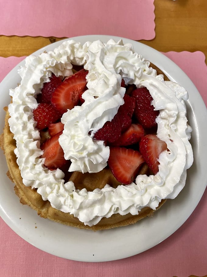 A mountain of whipped cream cradles fresh strawberries atop a golden waffle &ndash; proof that sometimes the best architecture isn't in buildings but on plates.