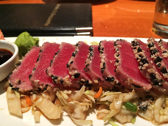 Sesame-crusted ahi tuna, seared rare and sliced with precision, resting on a bed of Asian slaw&mdash;proof that art exists on plates, not just walls.