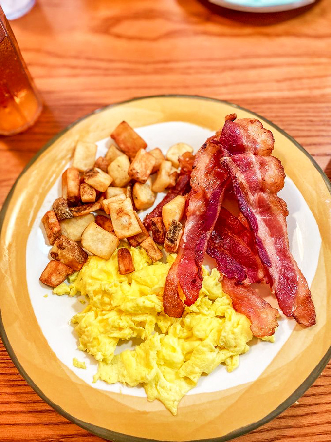 Breakfast's holy trinity: golden scrambled eggs, crispy home fries, and bacon so perfectly cooked it should have its own Instagram account.