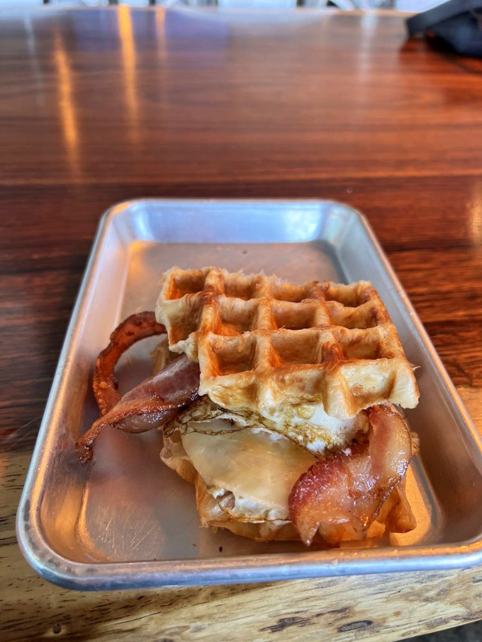 This breakfast sandwich doesn't just break the fast&mdash;it shatters it with crispy bacon and golden waffle perfection. Morning salvation on a metal tray.