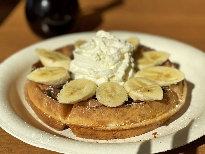 This banana waffle doesn't just say "good morning"—it serenades you with caramelized fruit and a cloud of whipped cream that melts into those perfect grid pockets.