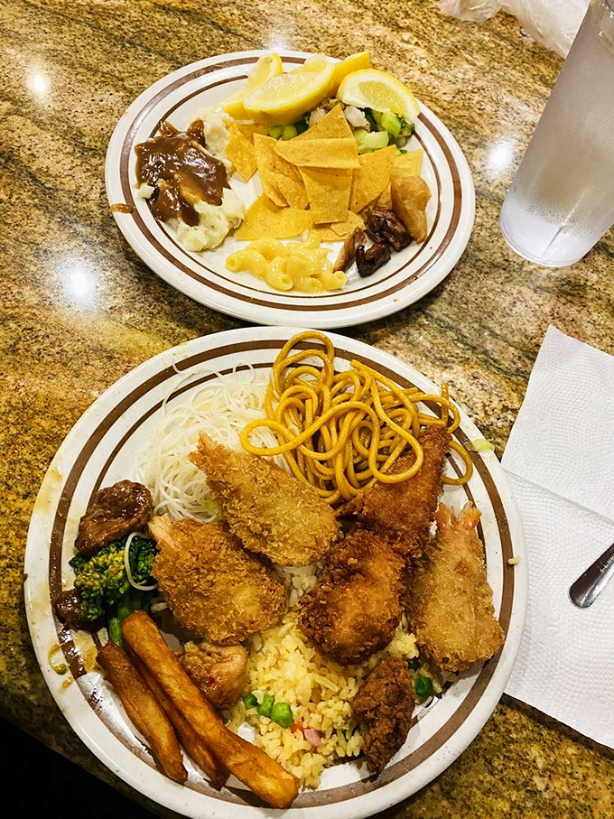 When your plate becomes a metropolitan skyline of fried delights, crispy shrimp towering over a landscape of noodles and rice. 