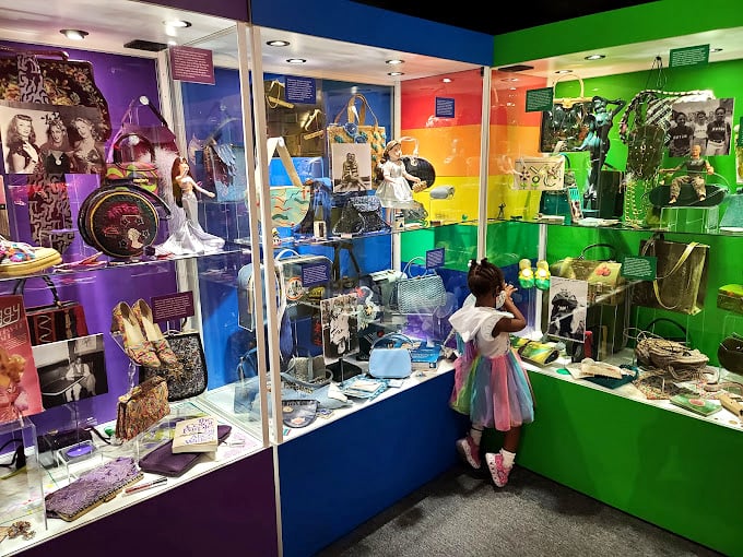 Colorful decade-by-decade displays captivate visitors of all ages, proving handbag history isn't just for grown-ups.