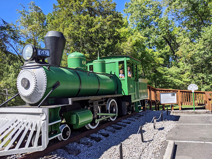 All aboard nostalgia! This vintage green locomotive stands guard, a cheerful sentinel preserving the park's railroad heritage.