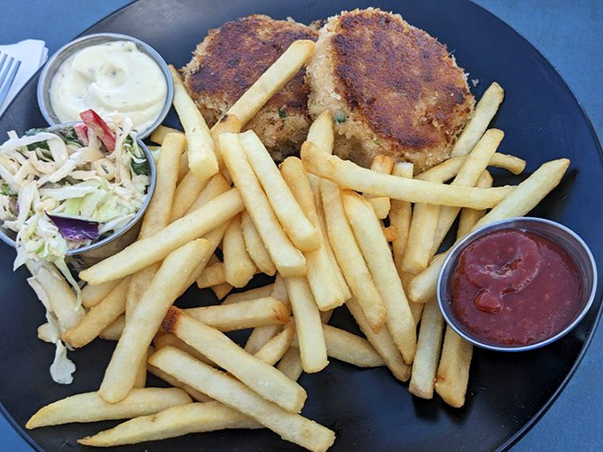 Golden-brown crab cakes flanked by crispy fries and fresh slaw &ndash; a holy trinity of seafood satisfaction that might make you weep with joy.