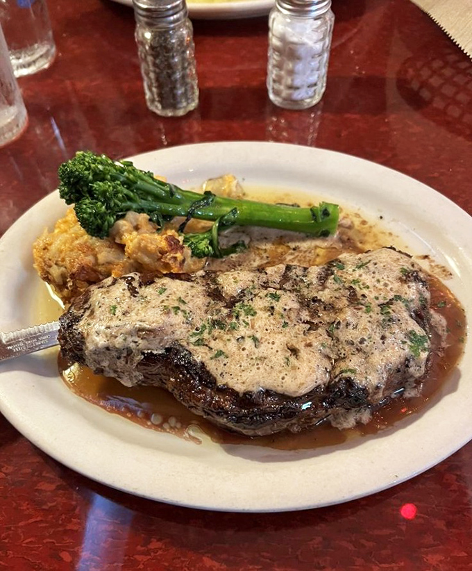 Treat yourself to a perfectly seared steak topped with creamy sauce, served alongside fresh broccolini for a truly delicious meal.