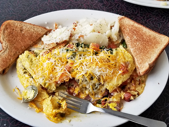 This isn't just an omelet; it's a morning masterpiece where cheese cascades over perfectly scrambled eggs alongside golden toast sentinels.