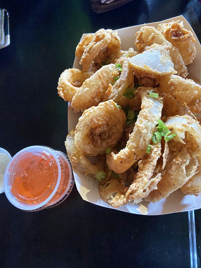 Golden-fried onion rings that crunch like autumn leaves, served with a dipping sauce that makes you consider drinking it straight.