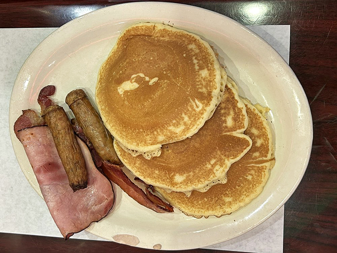 Pancakes stacked higher than Alabama humidity in August, with bacon and sausage playing supporting roles in this breakfast blockbuster.