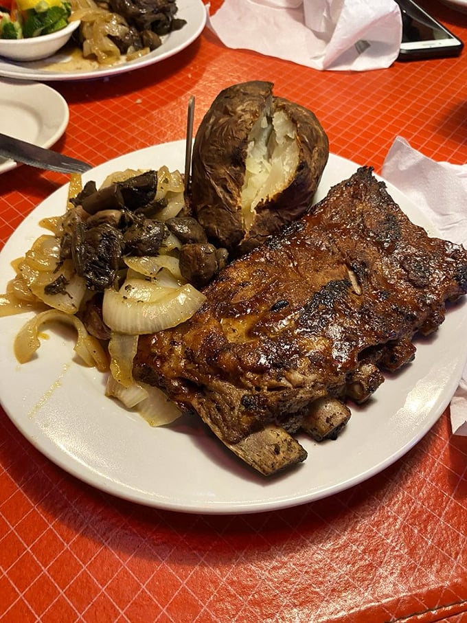 Behold the perfect marriage: flame-kissed ribs alongside grilled onions and a potato that's practically begging to be devoured.