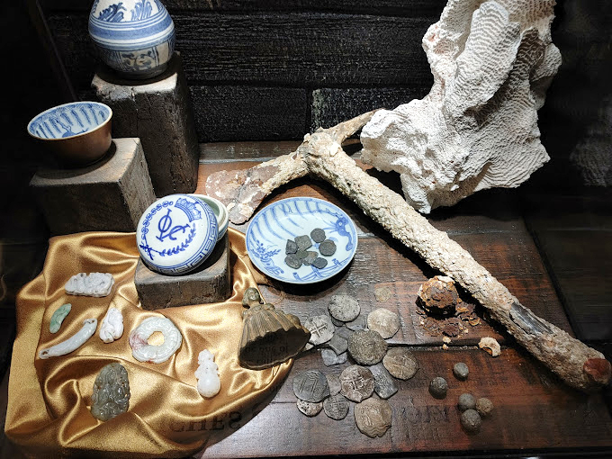 Pieces of eight and porcelain treasures&mdash;the real currency of the high seas, displayed exactly as they might have been found on the ocean floor.
