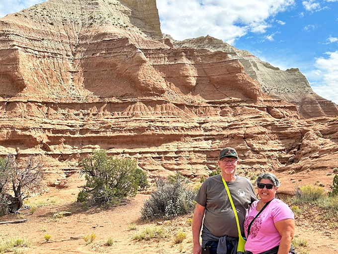 Happy explorers finding their moment of geological bliss. The layered cliffs behind them tell Earth's story one sedimentary stripe at a time.