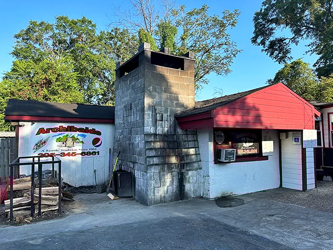 Archibald's cinderblock fortress and towering smokestack &ndash; BBQ architecture at its most honest. That woodpile isn't decoration; it's tomorrow's flavor.