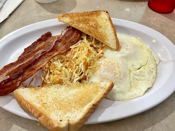 Breakfast perfection on a plate: golden hash browns, perfectly cooked eggs, and bacon that's achieved that mythical balance between crispy and chewy that philosophers have debated for centuries.
